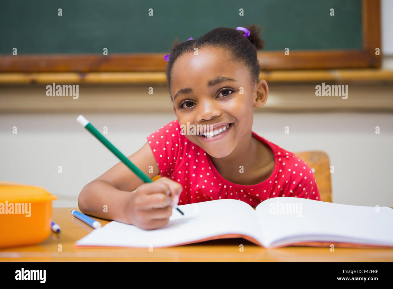 Cute pupils writing at desk in classroom Stock Photo - Alamy