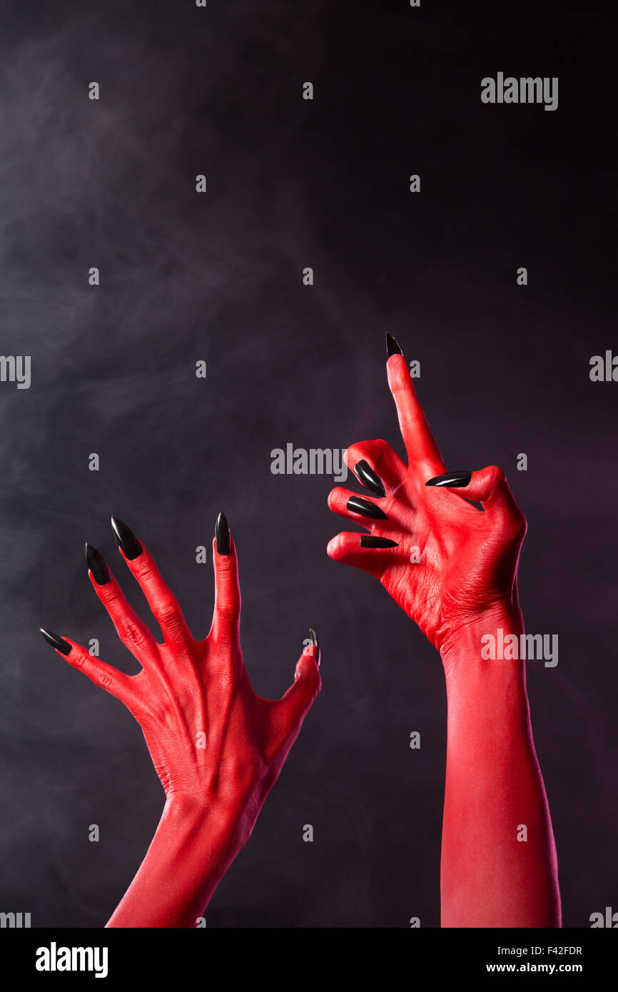 Scary red devil hands with black nails on smoky background with copy ...