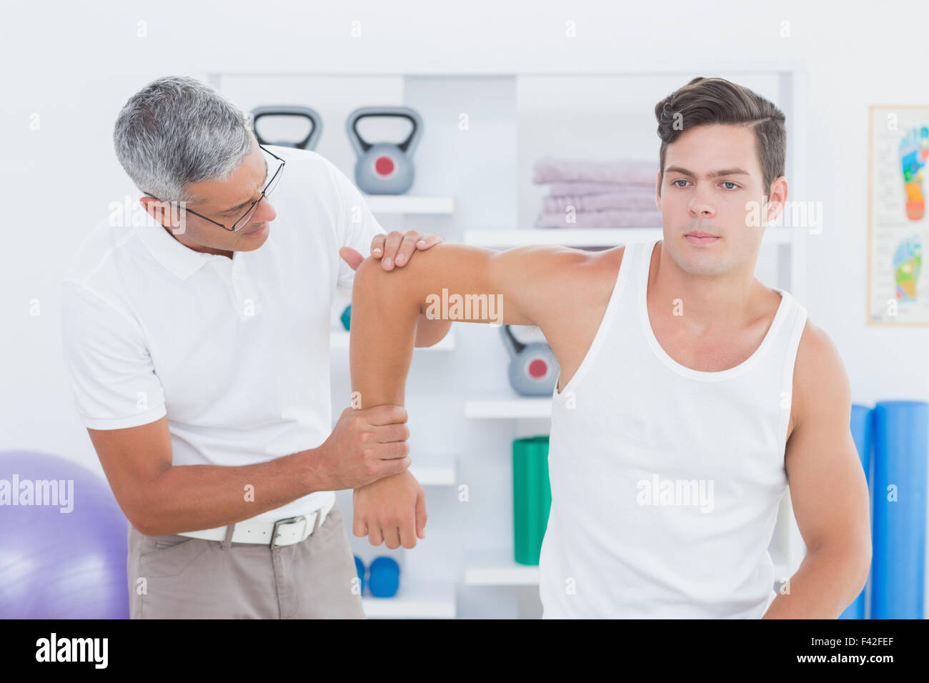 Doctor stretching a young man arm Stock Photo - Alamy
