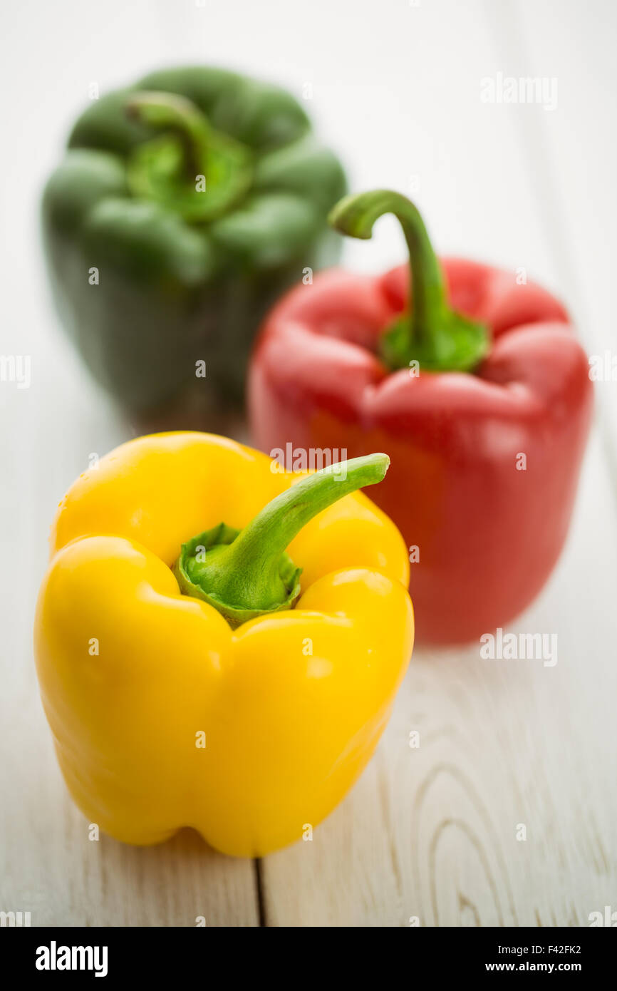 Three peppers on chopping board Stock Photo - Alamy