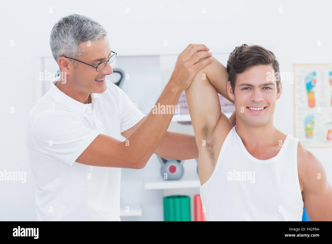 Doctor stretching a young man arm Stock Photo - Alamy