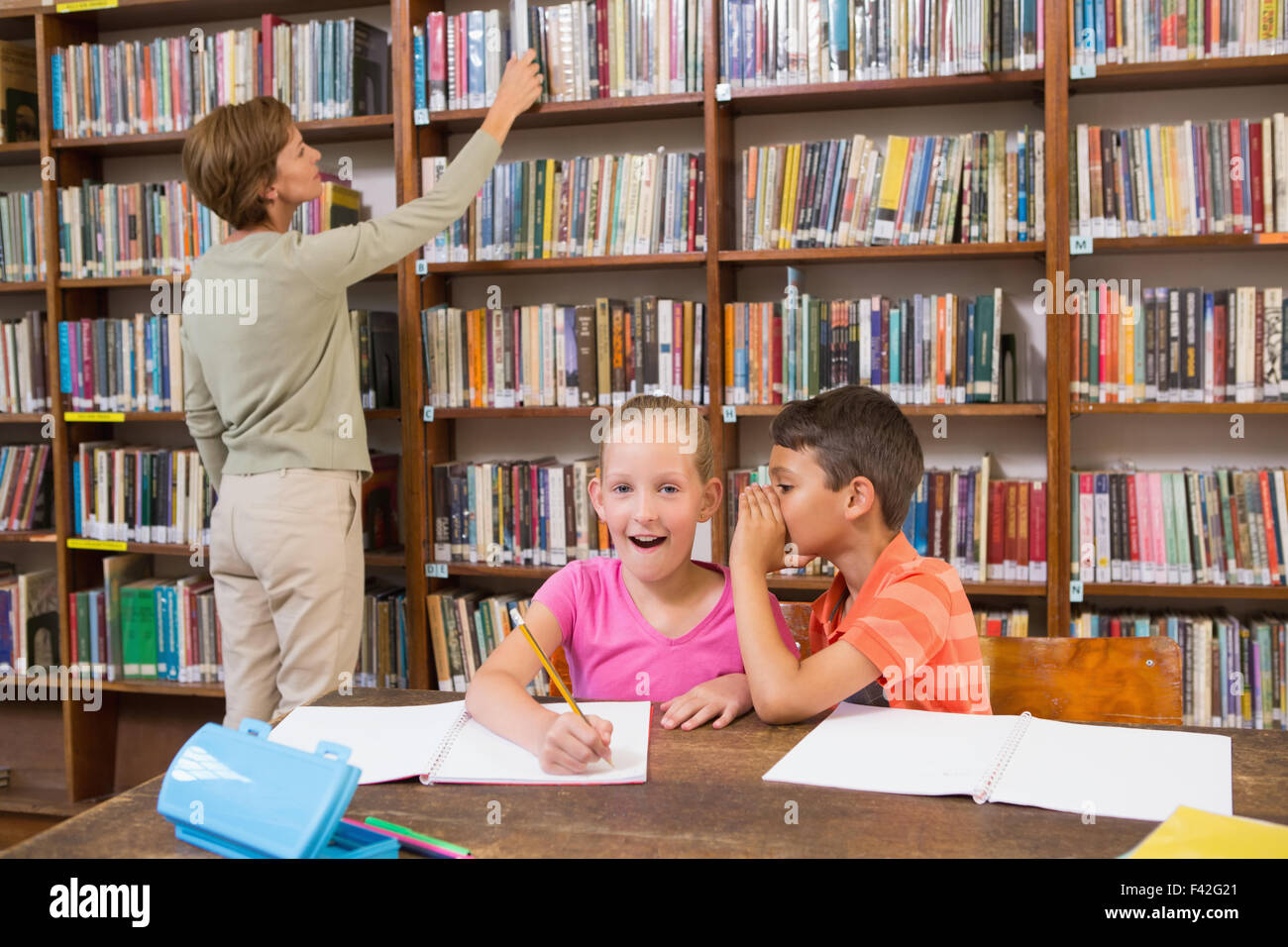 Cute pupils speaking at library Stock Photo - Alamy