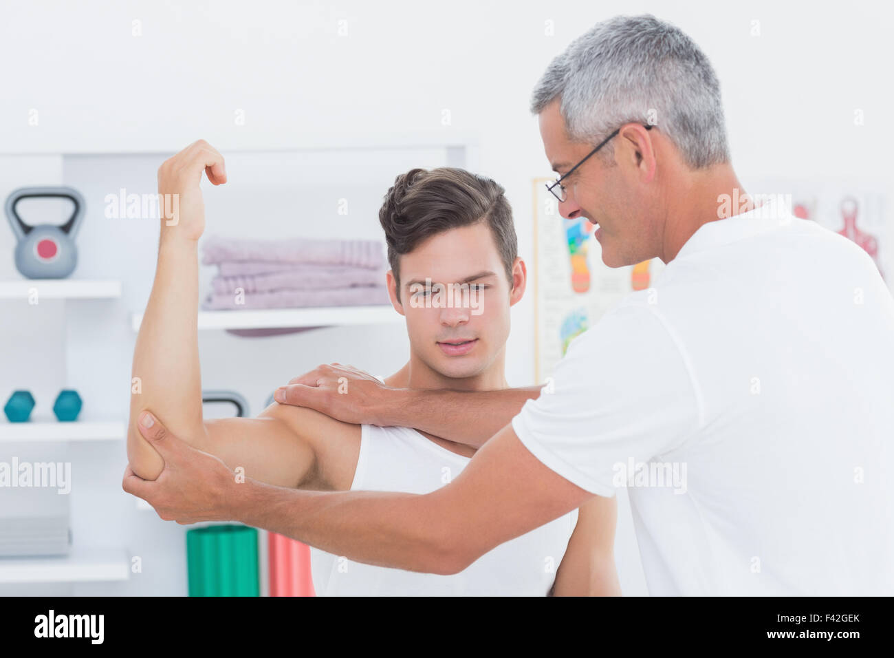 Doctor stretching a young man arm Stock Photo - Alamy