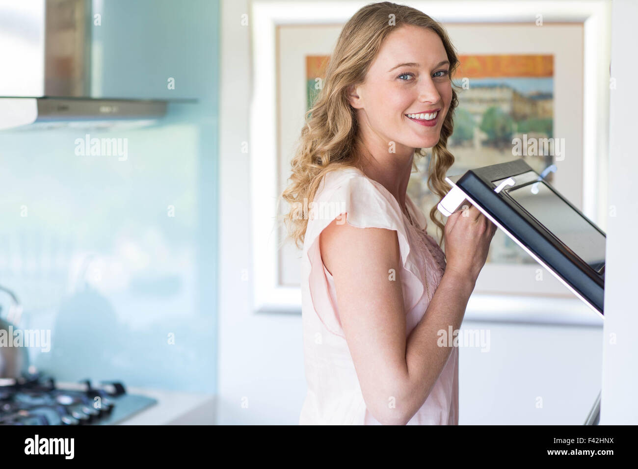 Pretty blonde opening the oven Stock Photo - Alamy