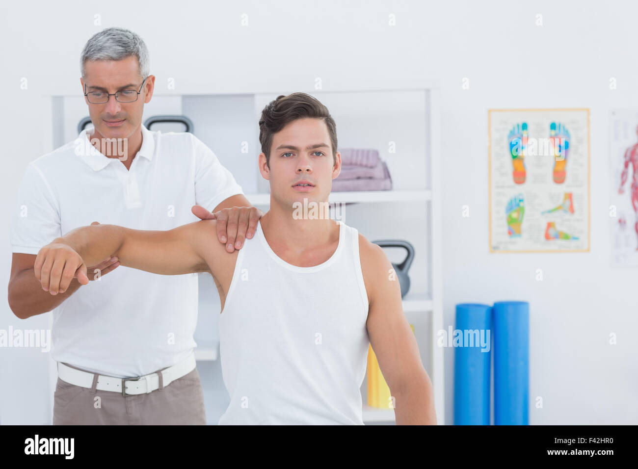 Doctor stretching a young man arm Stock Photo - Alamy
