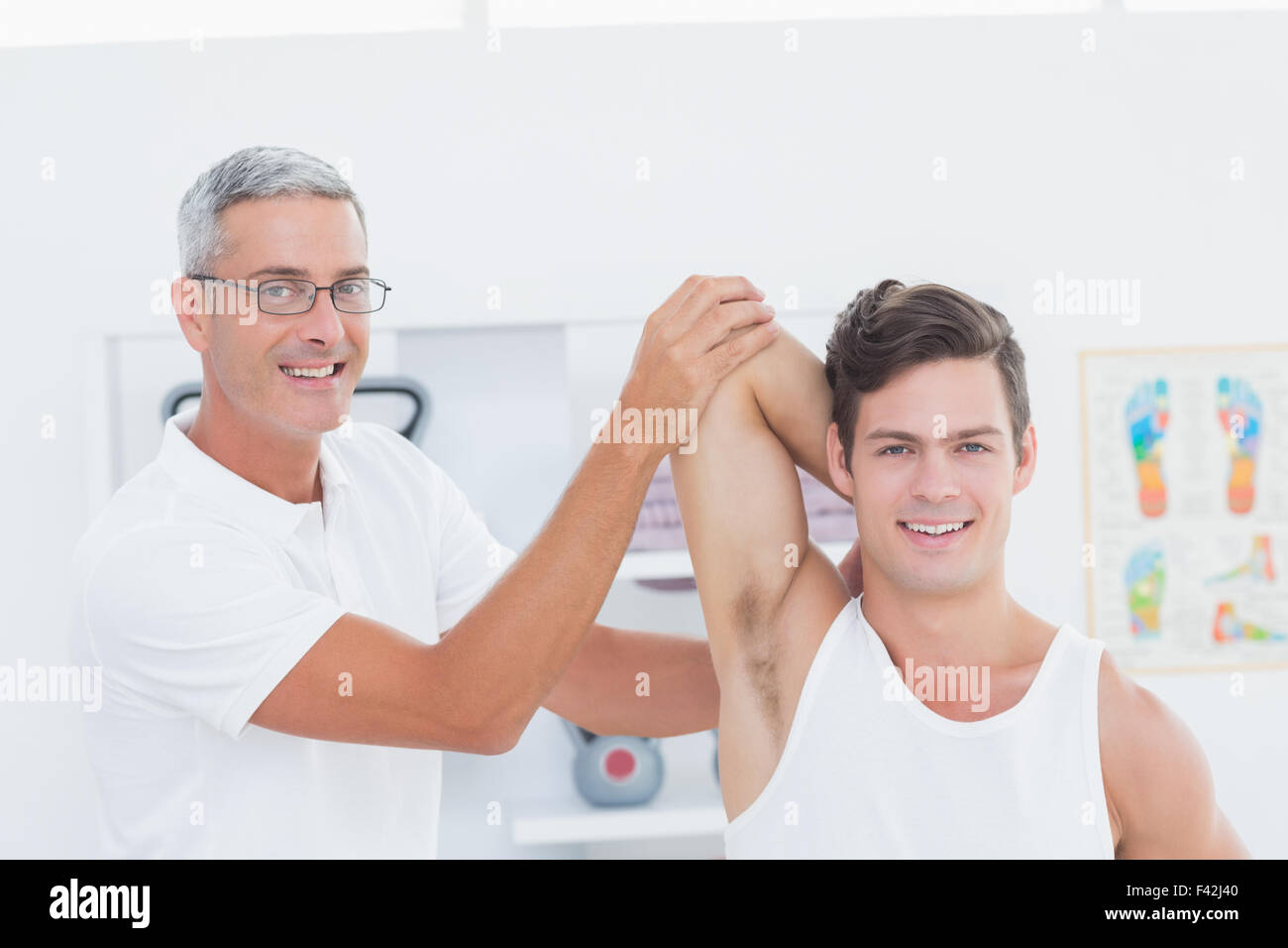 Doctor stretching a young man arm Stock Photo - Alamy