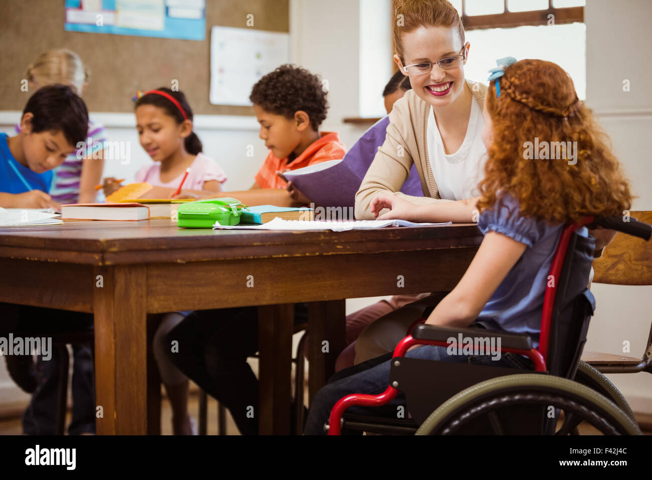 Teacher helping a disabled pupil Stock Photo - Alamy