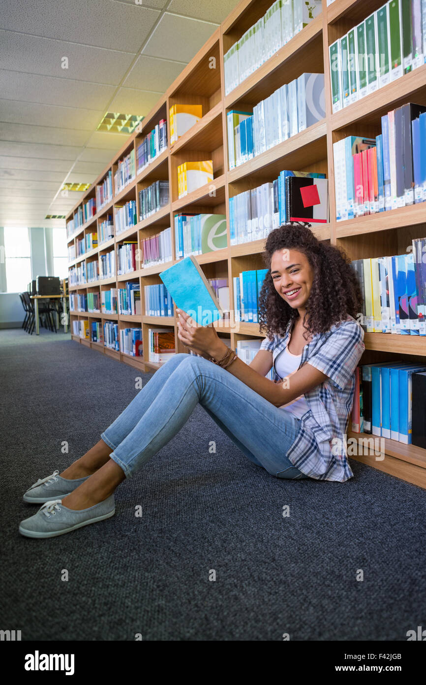 Student sitting on floor in library reading Stock Photo - Alamy