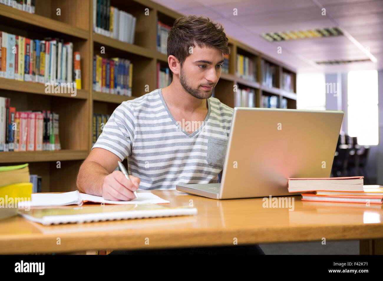 Student studying in the library with laptop Stock Photo - Alamy