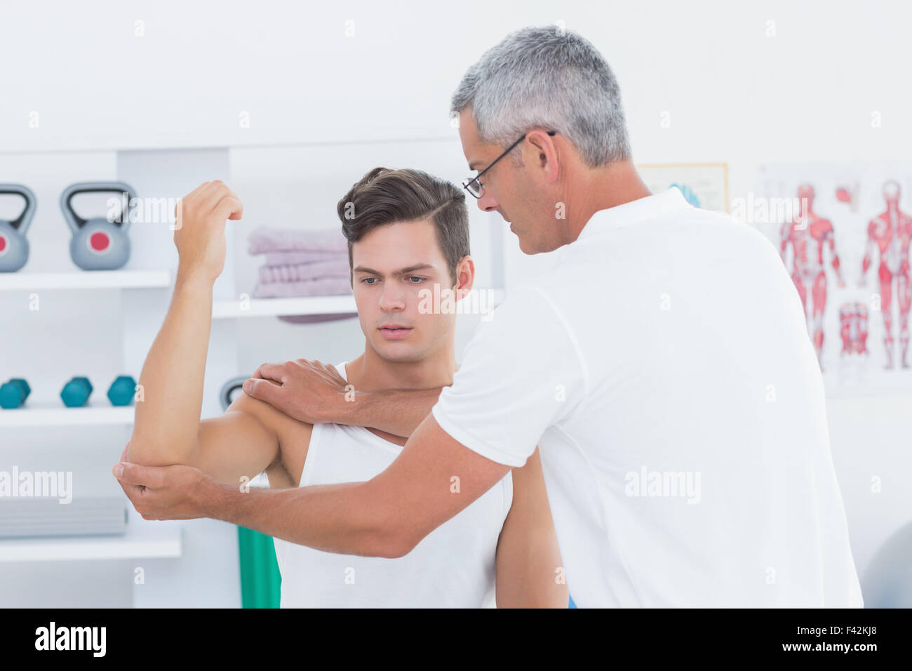 Doctor stretching a young man arm Stock Photo - Alamy