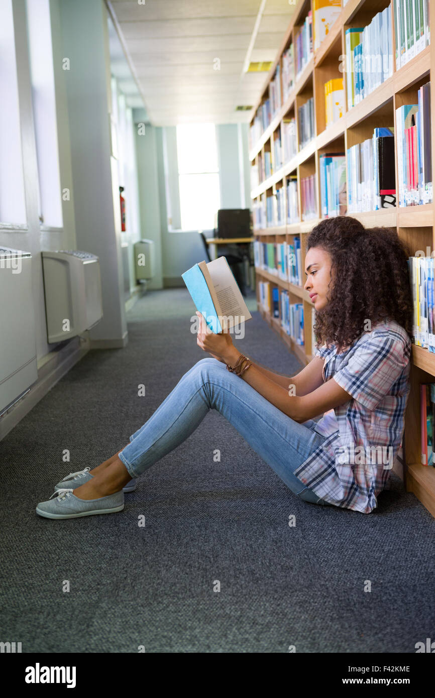 Student sitting on floor in library reading Stock Photo - Alamy