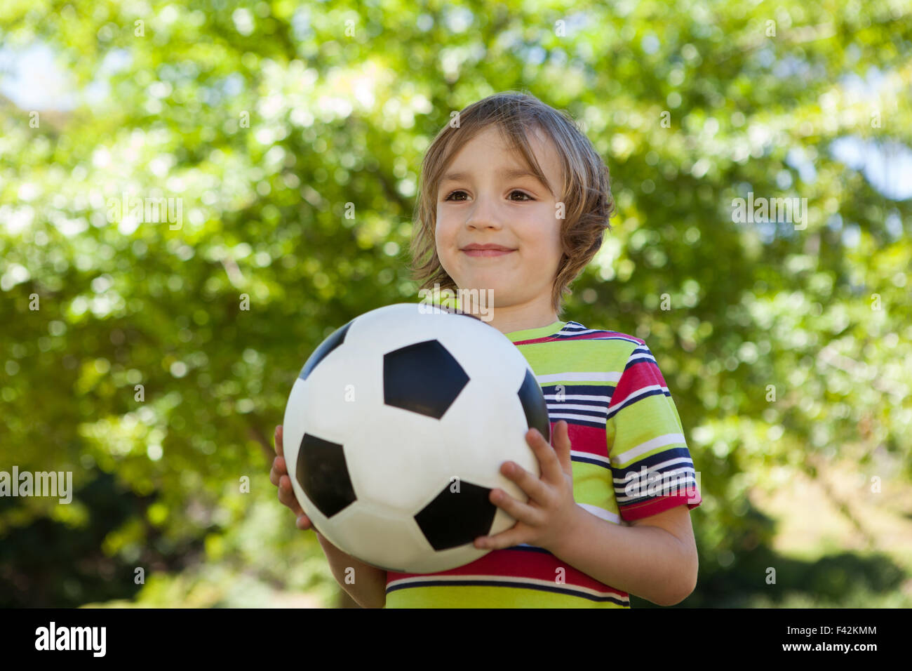 Happy little boy holding football Stock Photo - Alamy