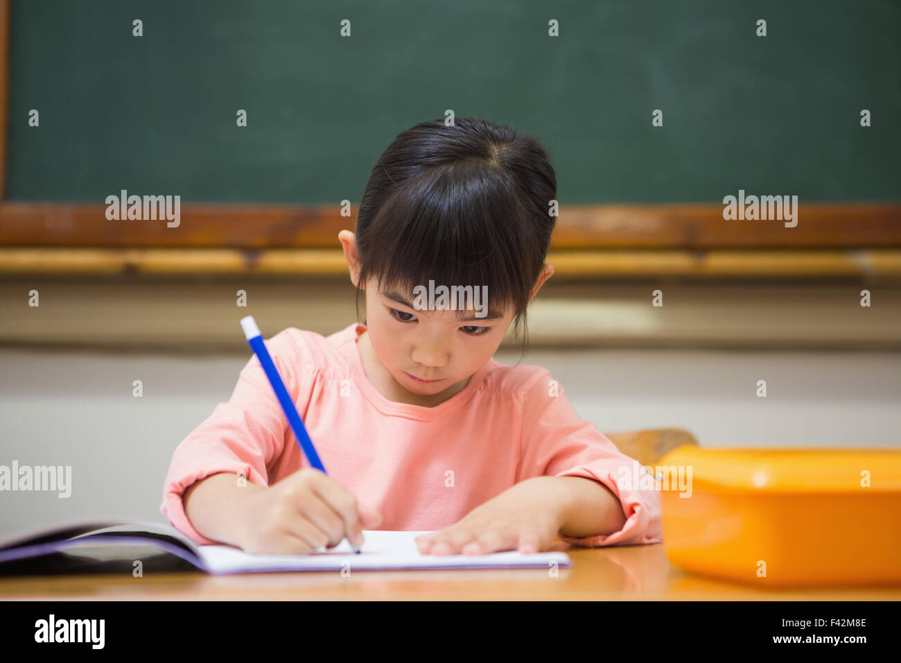 Cute pupil writing at desk in classroom Stock Photo - Alamy