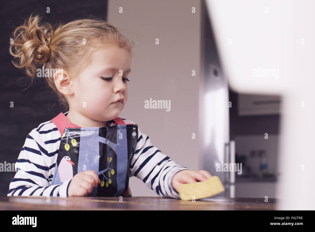 Little girl wiping table with spong Stock Photo - Alamy