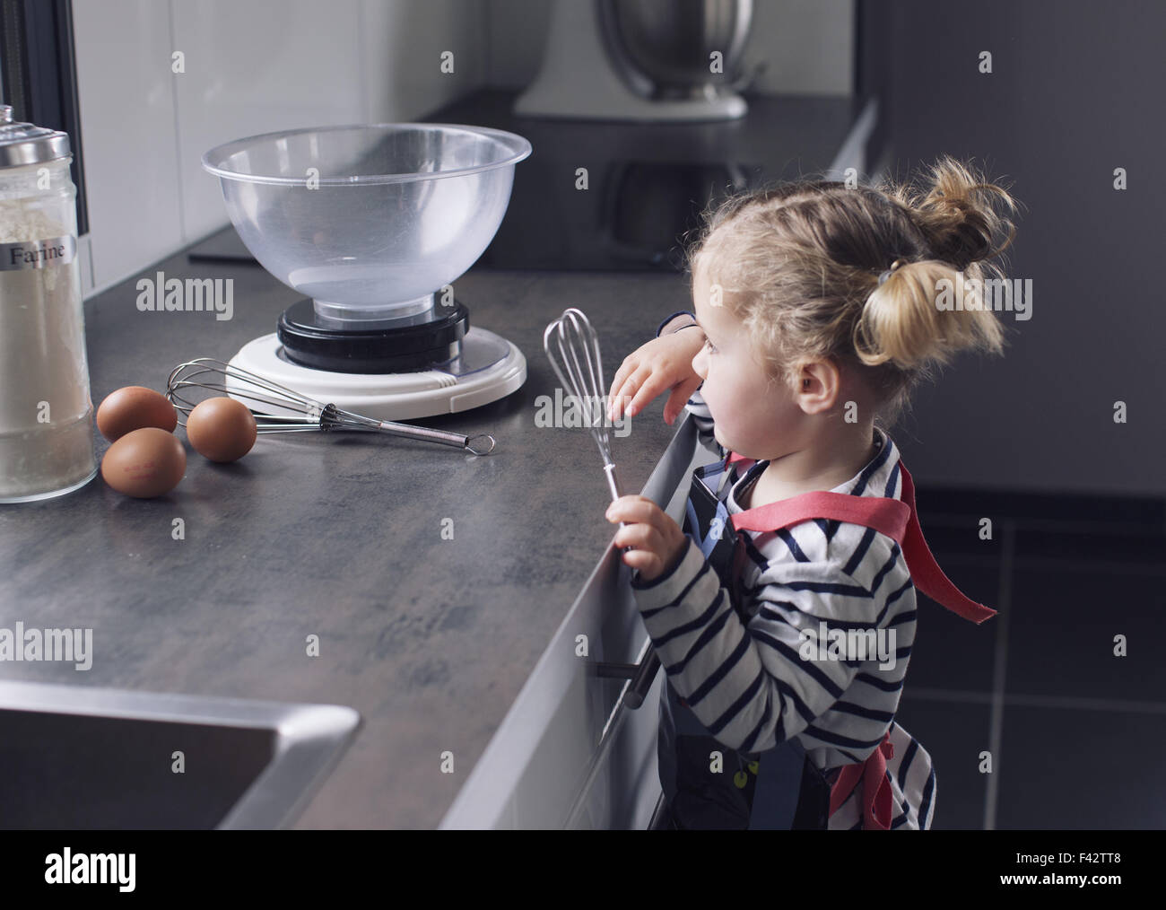 Little girl holding whisk in kitchen Stock Photo - Alamy