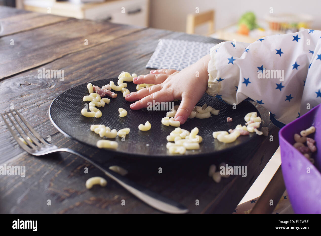 Child eating macaroni with her hand, cropped Stock Photo - Alamy
