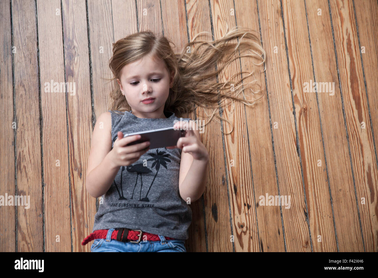 Little girl lying on floor using smartphone Stock Photo - Alamy