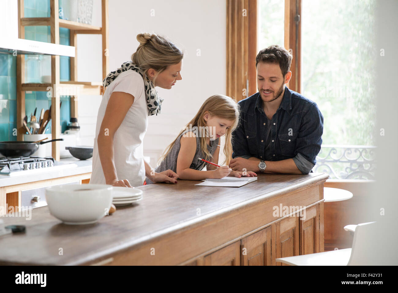 Parents helping young daughter with lessons Stock Photo - Alamy