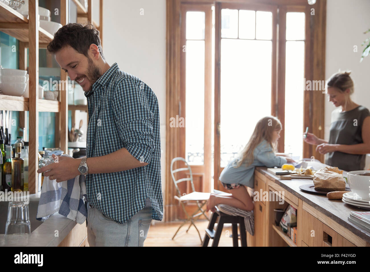 Family in kitchen, man drying dishes in foreground Stock Photo - Alamy