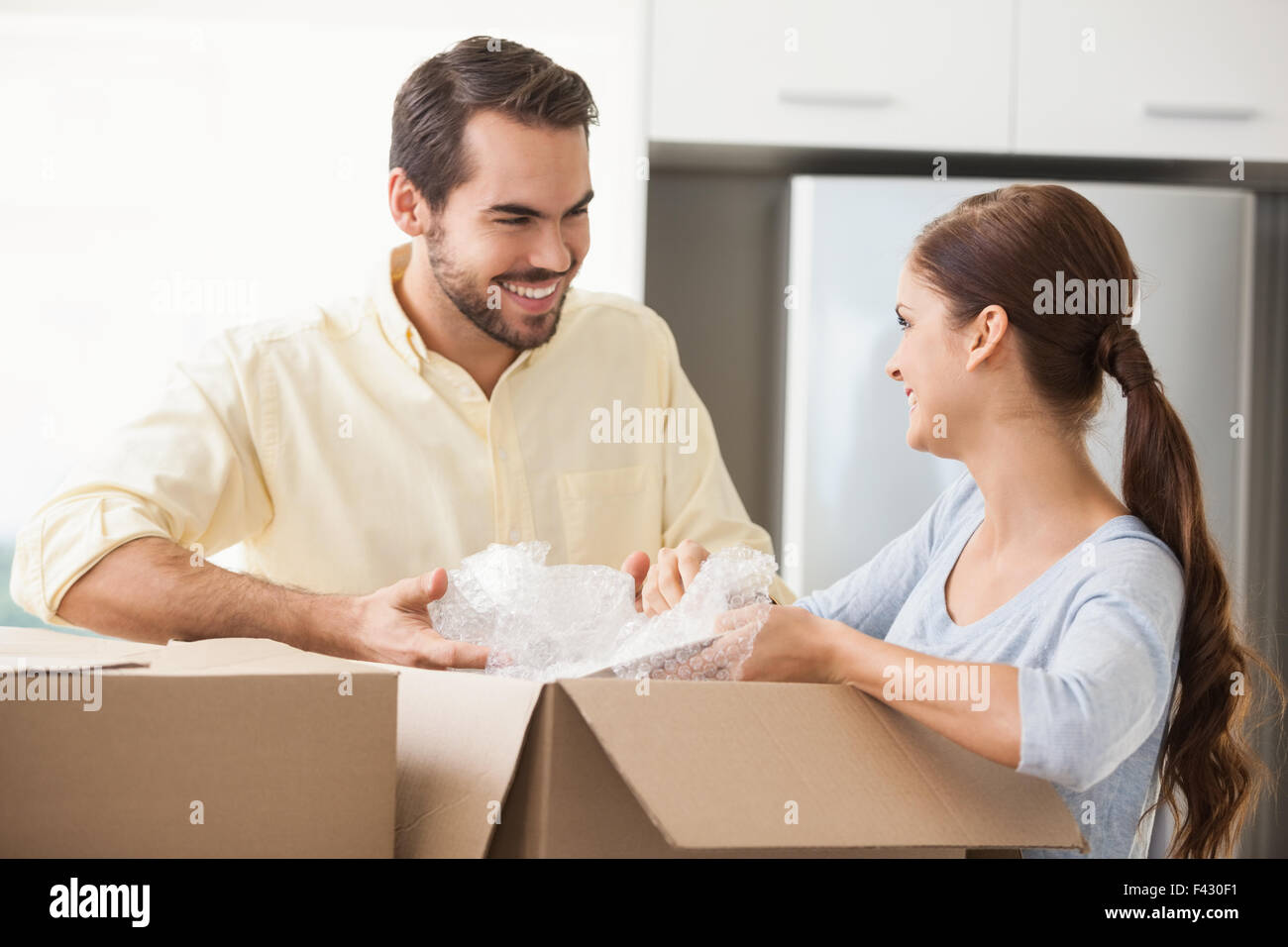 Young couple unpacking boxes in kitchen Stock Photo - Alamy