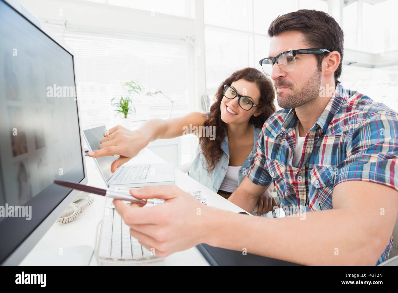 Smiling colleagues pointing computer together Stock Photo - Alamy