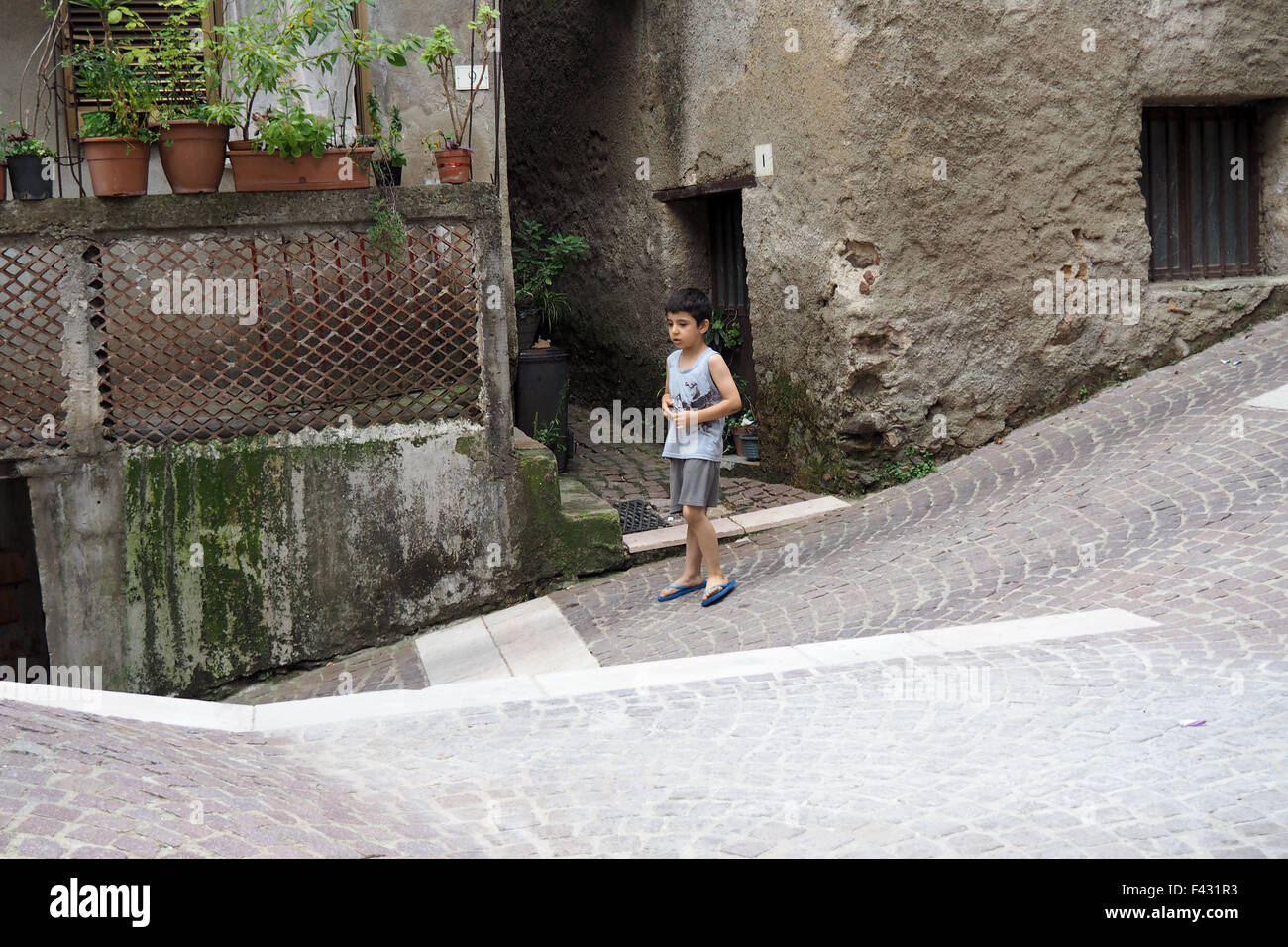 A young boy standing on a sloping pavement in an Italian village Stock ...