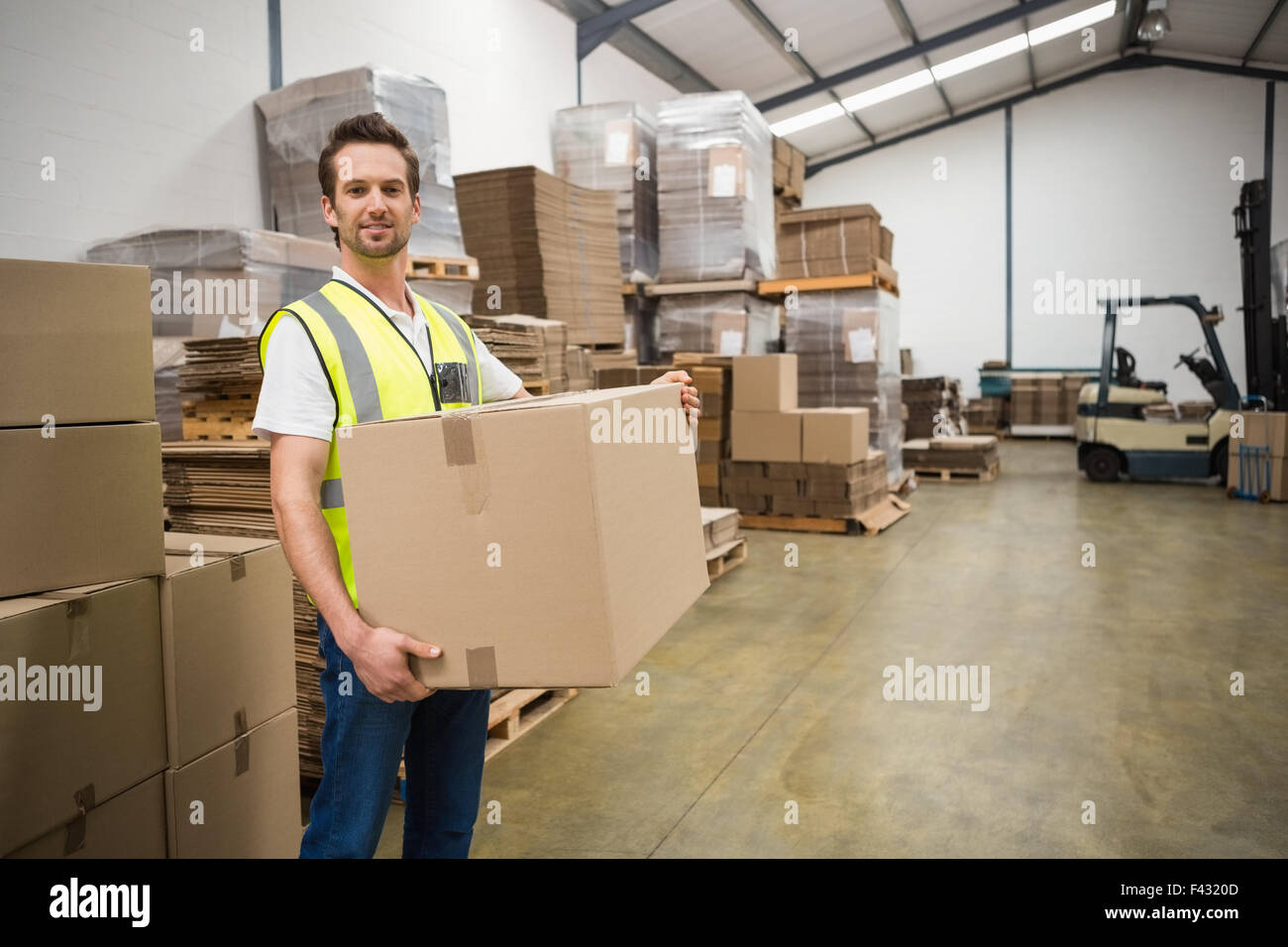 Worker carrying box in warehouse Stock Photo - Alamy