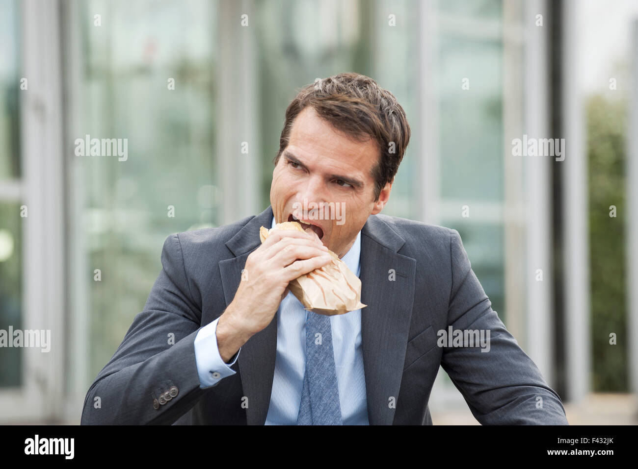Businessman eating sandwich outdoors Stock Photo - Alamy