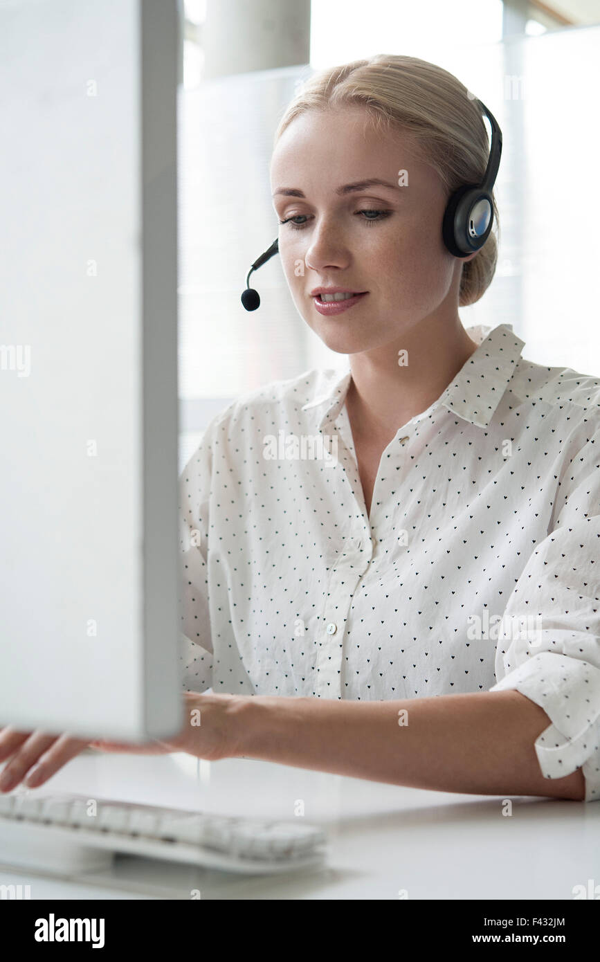 Woman using desktop computer and headset in office Stock Photo - Alamy