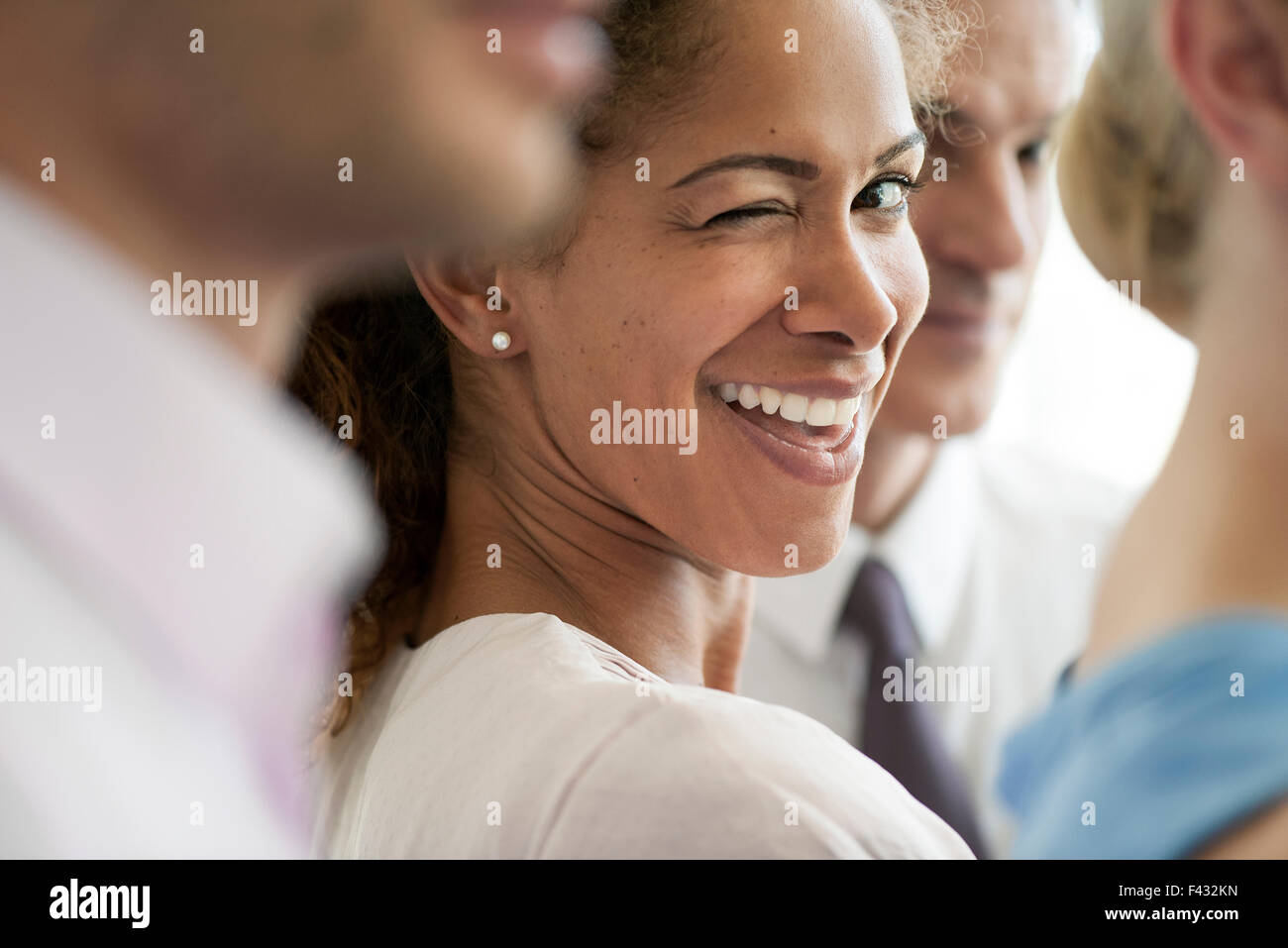 Woman with colleagues, winking playfully at camera Stock Photo - Alamy