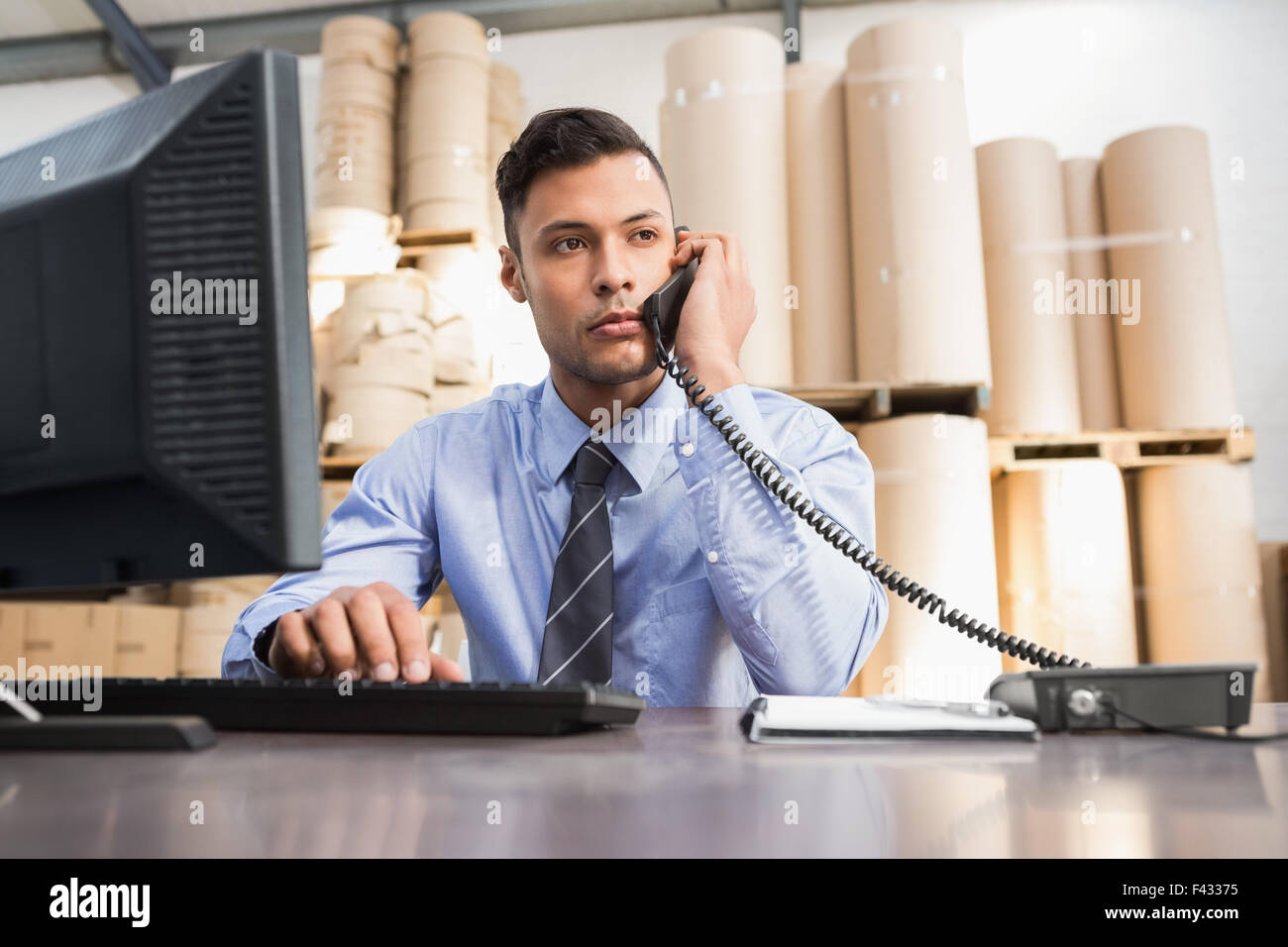 Warehouse manager using cellphone and laptop Stock Photo - Alamy