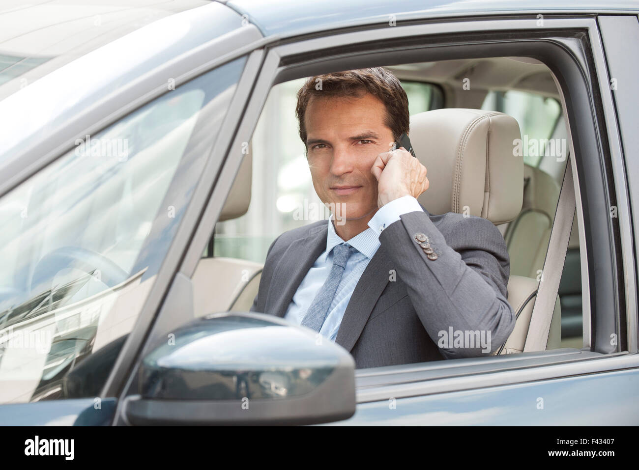 Businessman using cell phone while driving car Stock Photo - Alamy