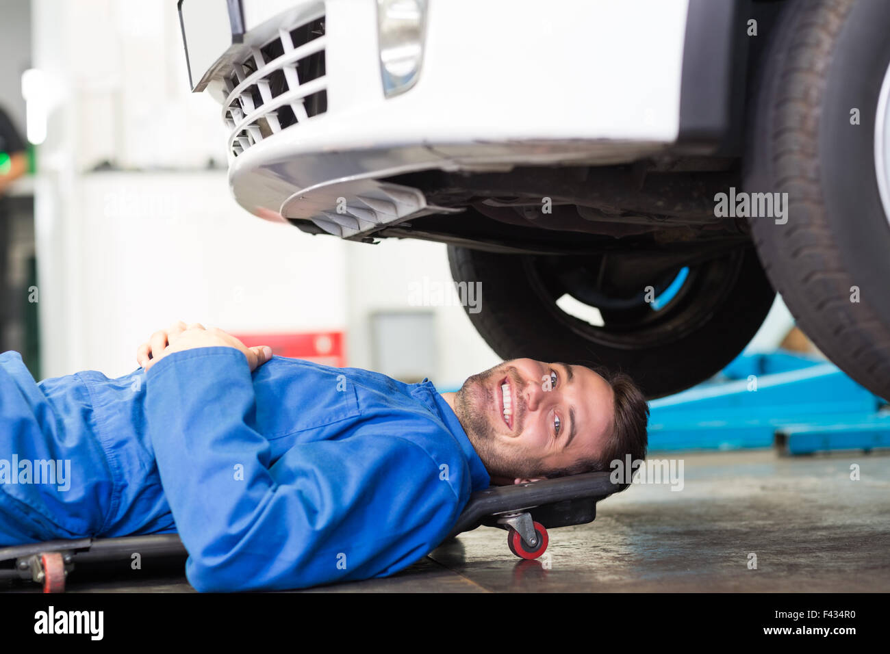 Smiling mechanic lying on trolley Stock Photo - Alamy
