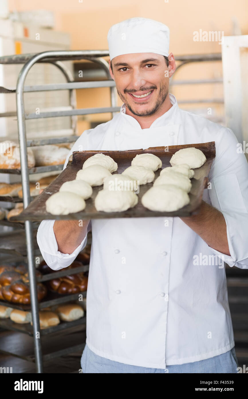 Smiling baker holding tray of raw dough Stock Photo - Alamy