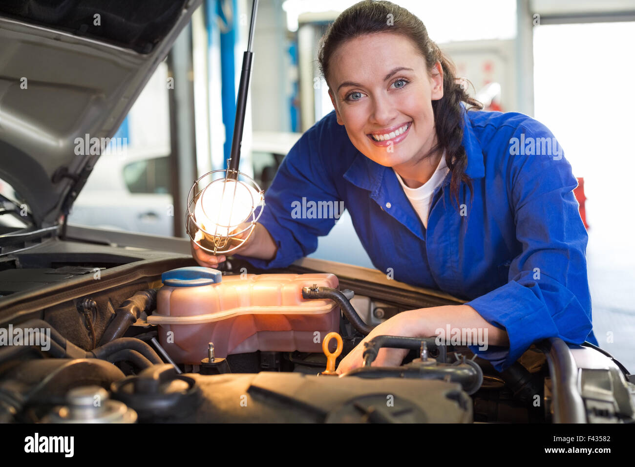Mechanic smiling at the camera with torch Stock Photo - Alamy