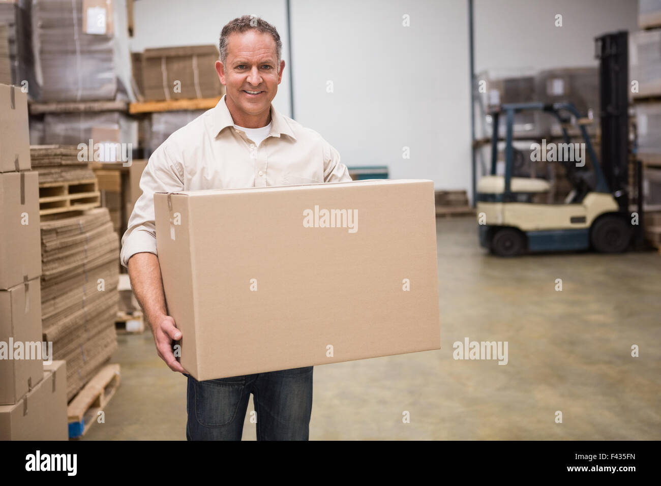 Smiling worker carrying a box Stock Photo - Alamy
