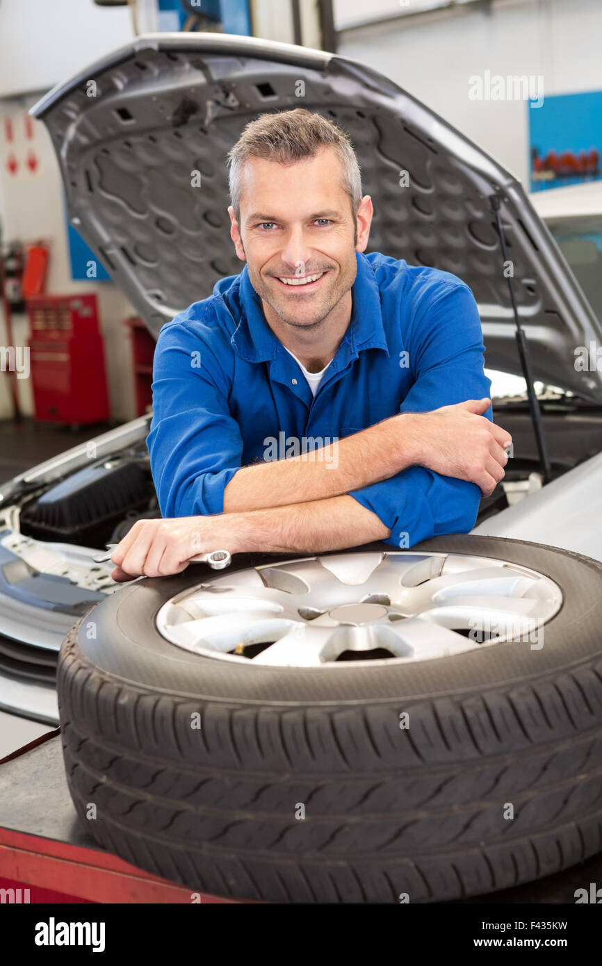 Mechanic smiling at the camera with tire Stock Photo - Alamy