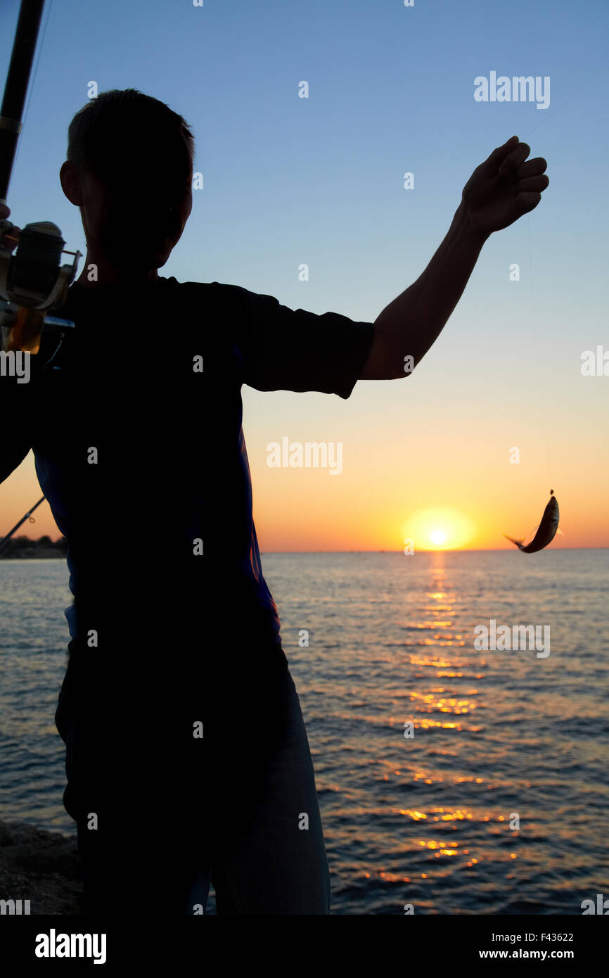 Fisherman fishes at the sunset Stock Photo - Alamy
