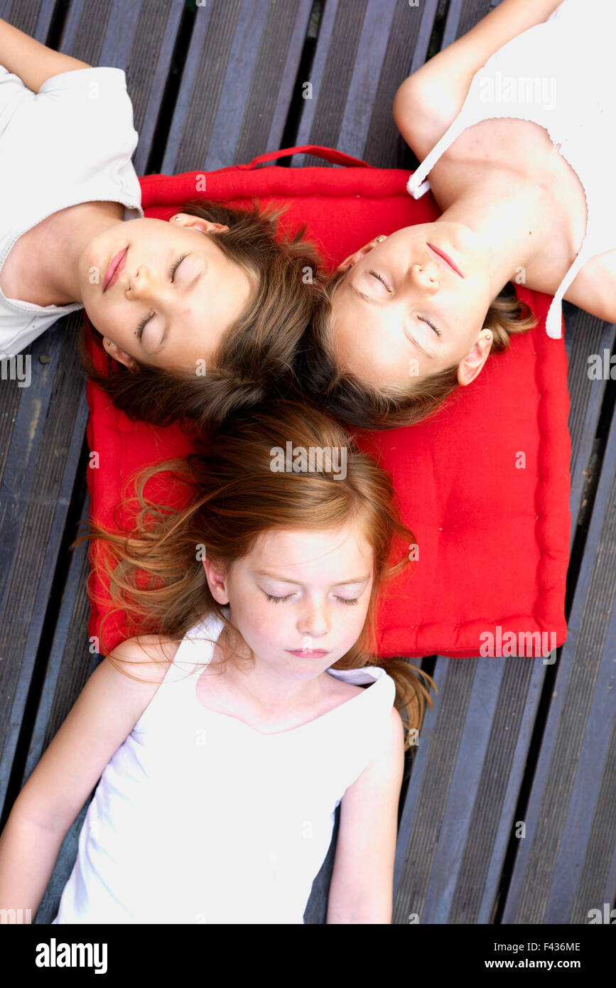 Girls napping outdoors with heads resting on shared cushion Stock Photo ...