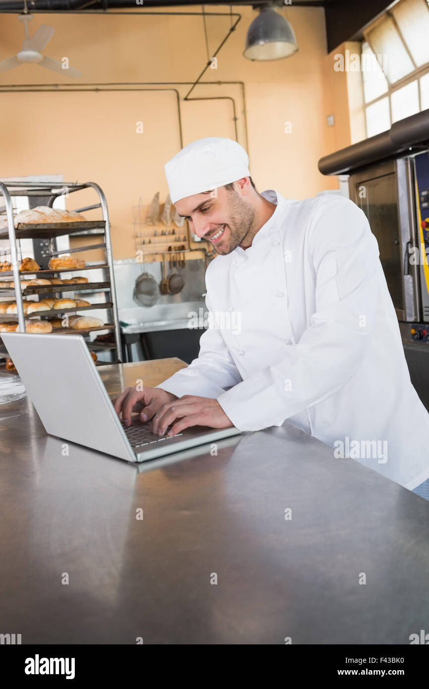 Smiling baker using laptop on worktop Stock Photo - Alamy