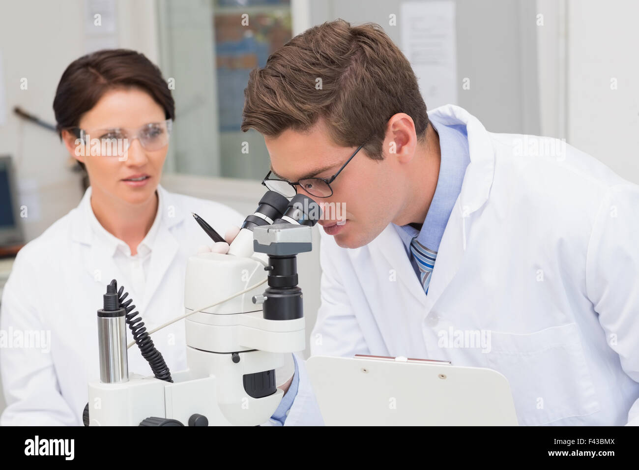 Scientists looking attentively in microscope Stock Photo - Alamy