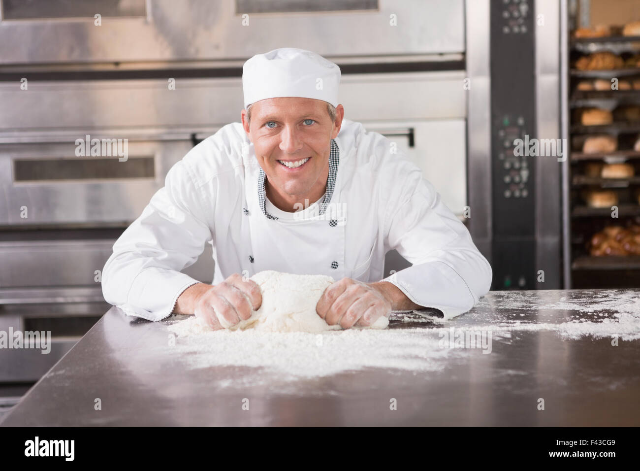Smiling baker kneading dough on counter Stock Photo - Alamy