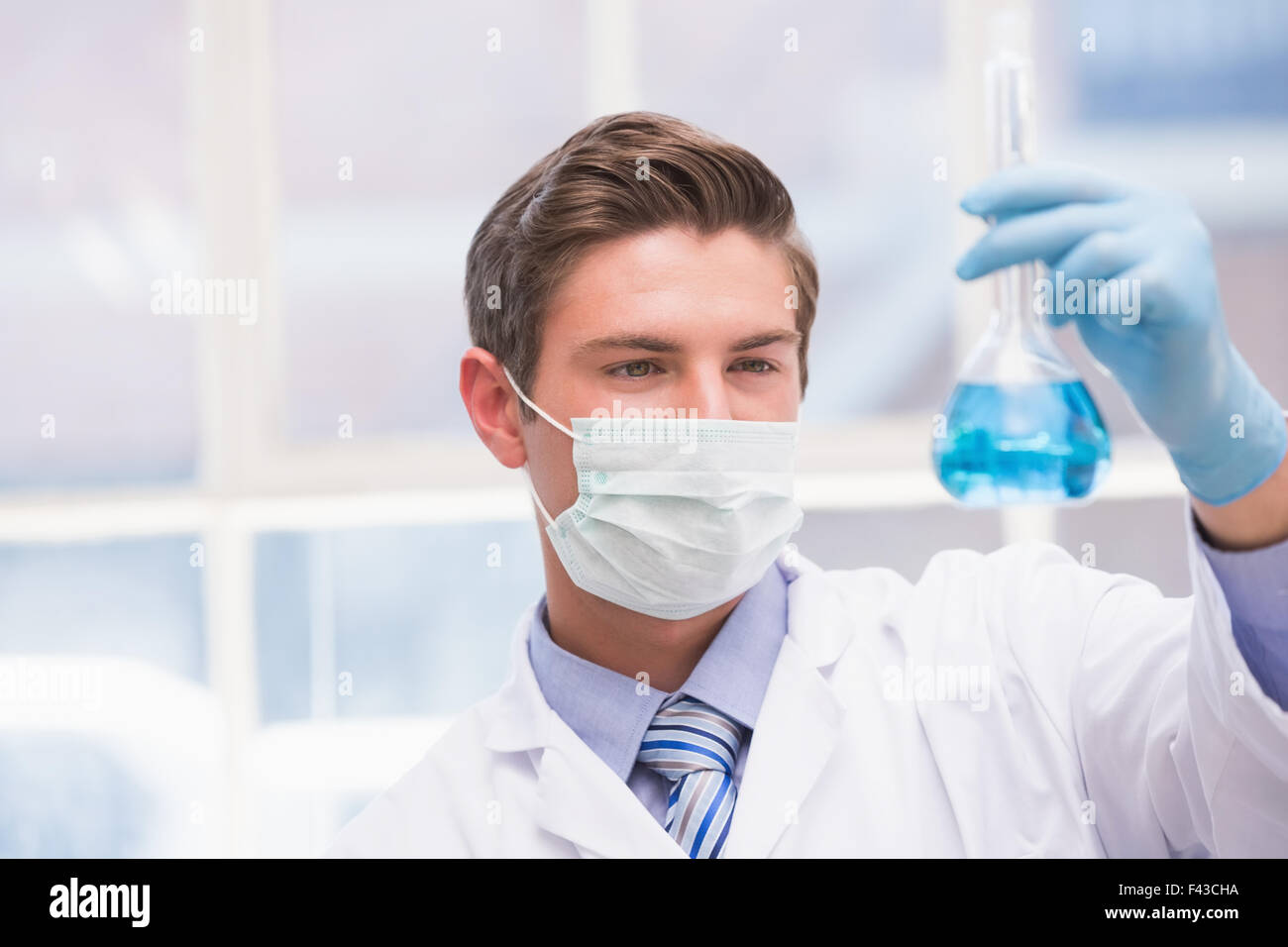 Scientist examining beaker with blue fluid Stock Photo - Alamy