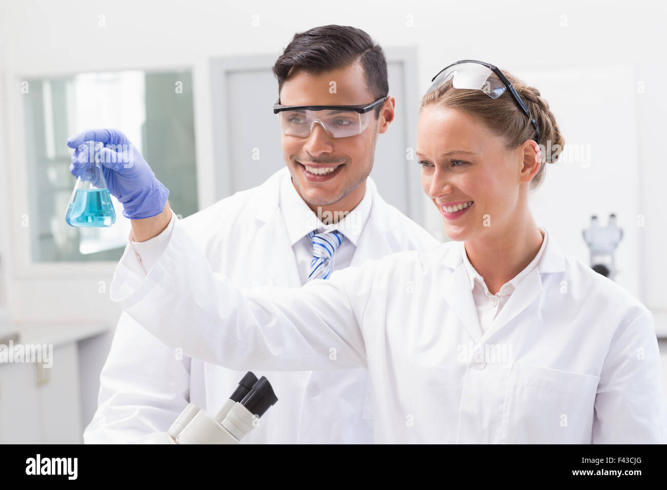 Smiling scientists looking at beaker Stock Photo - Alamy