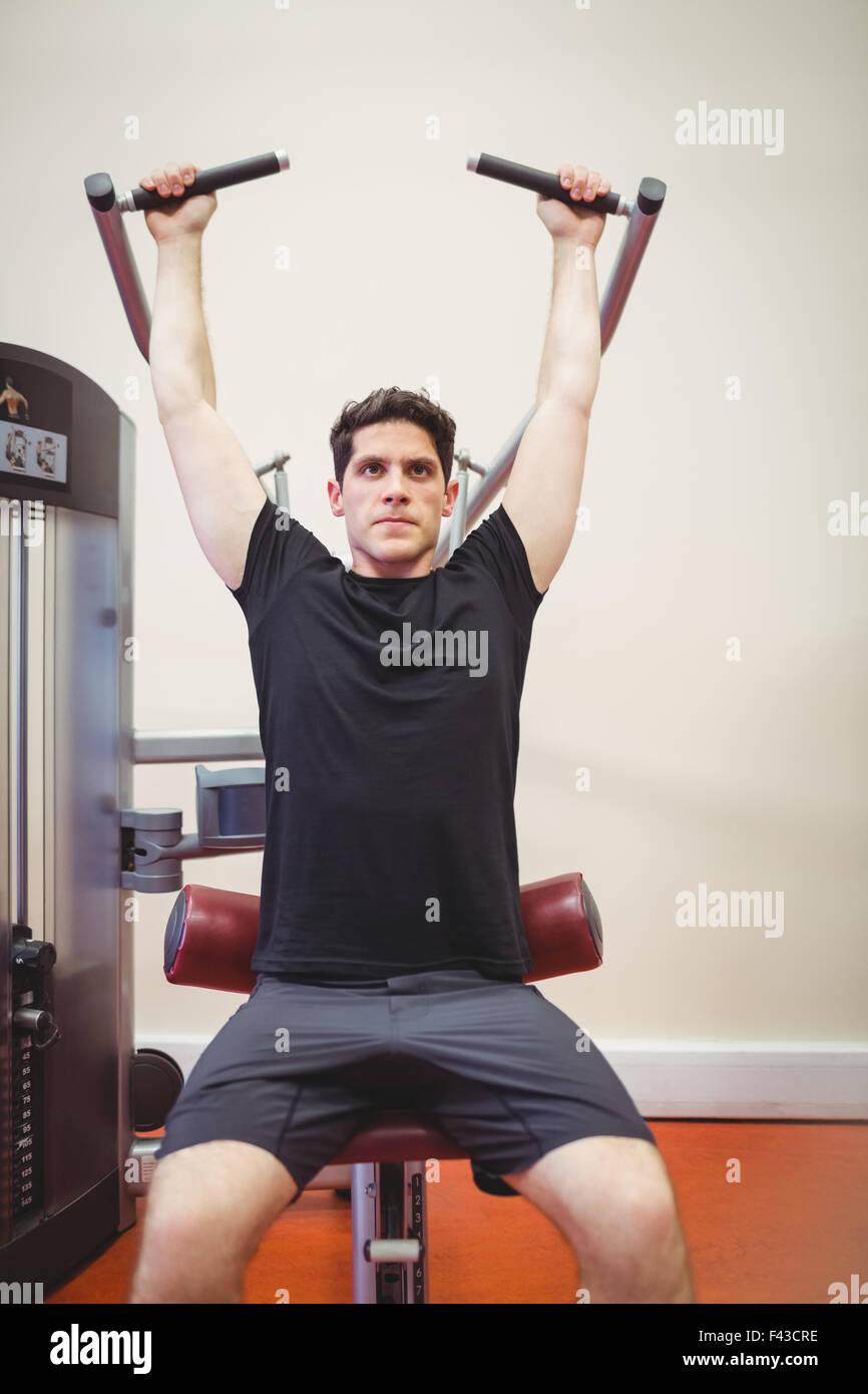 Fit man using weights machine for arms Stock Photo - Alamy