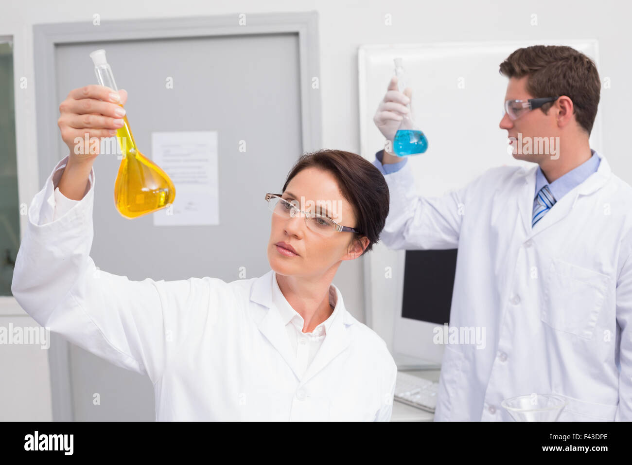 Scientists looking attentively at beakers Stock Photo - Alamy
