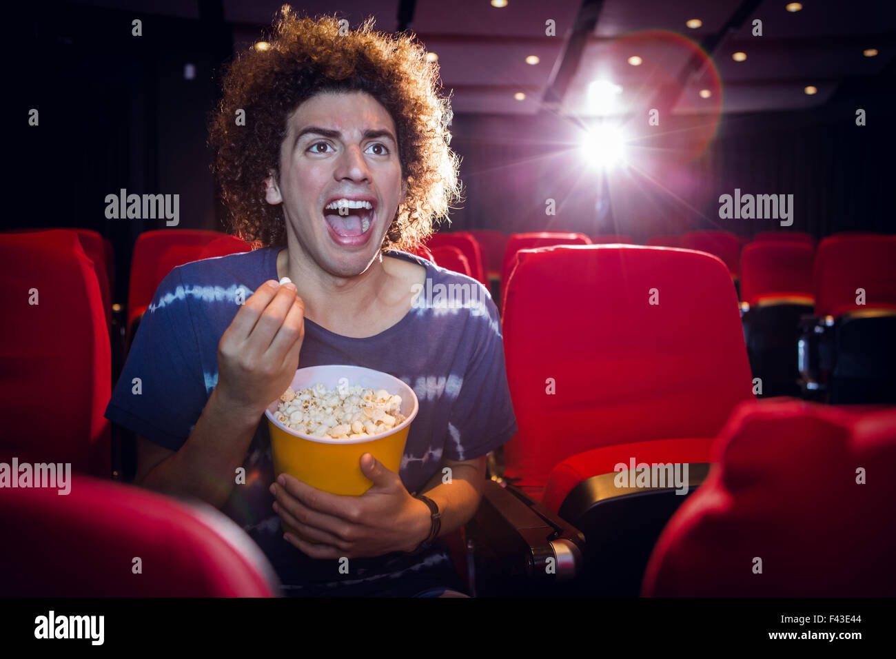 Happy young man watching a film Stock Photo - Alamy