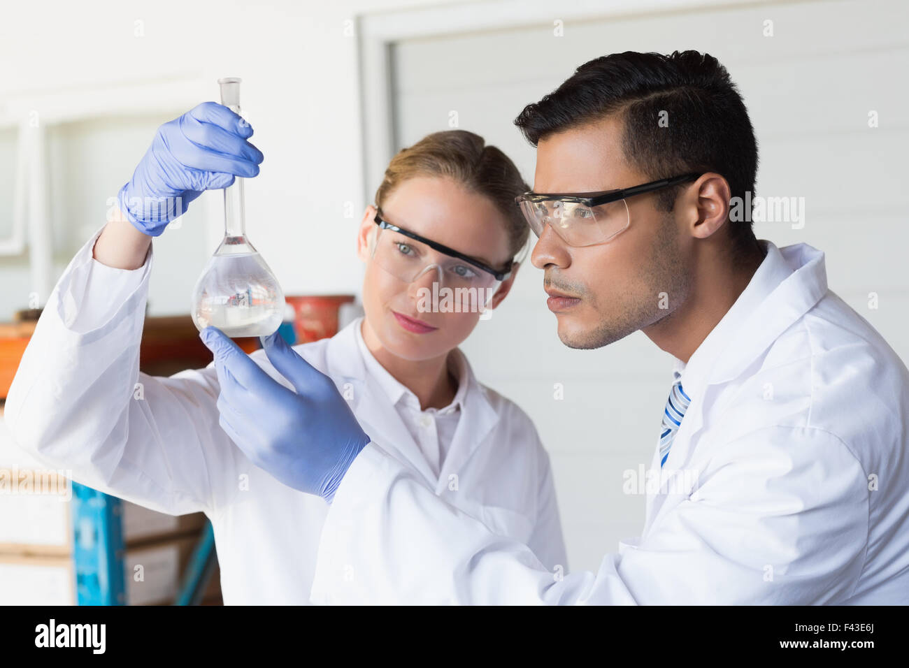 Concentrated scientists looking at beaker Stock Photo - Alamy