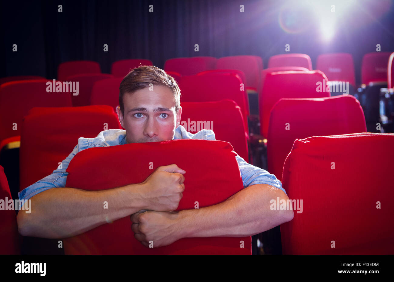 Young man watching a scary film Stock Photo - Alamy