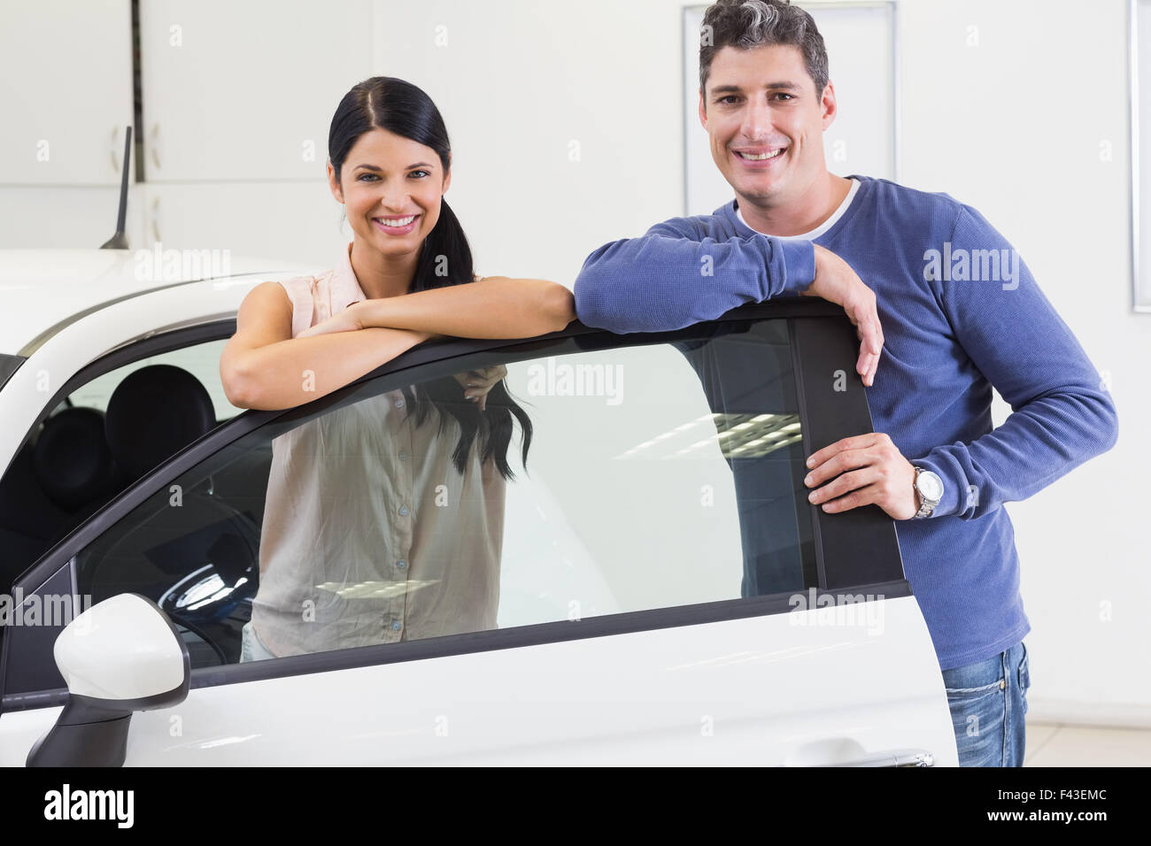 Smiling couple leaning on car Stock Photo - Alamy